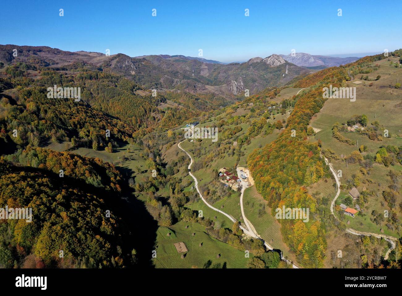 Aerial view of village dirt road in the mountains. Autumn forest and ...