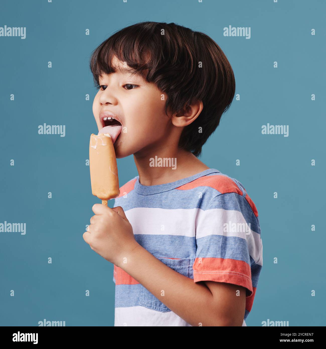Japanese boy, bite and ice cream in studio background with sweet snack ...