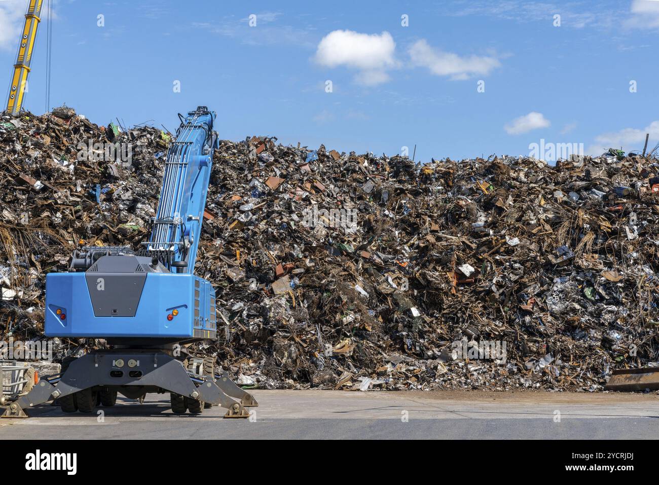 A large pile of scrap metal and waste at a recycling plant with a blue ...