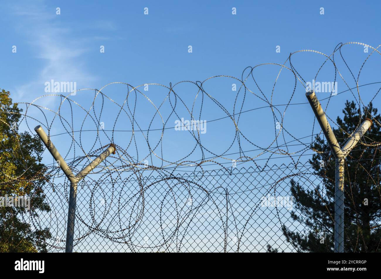A close-up view of a tall barbed wire fence on the border between ...