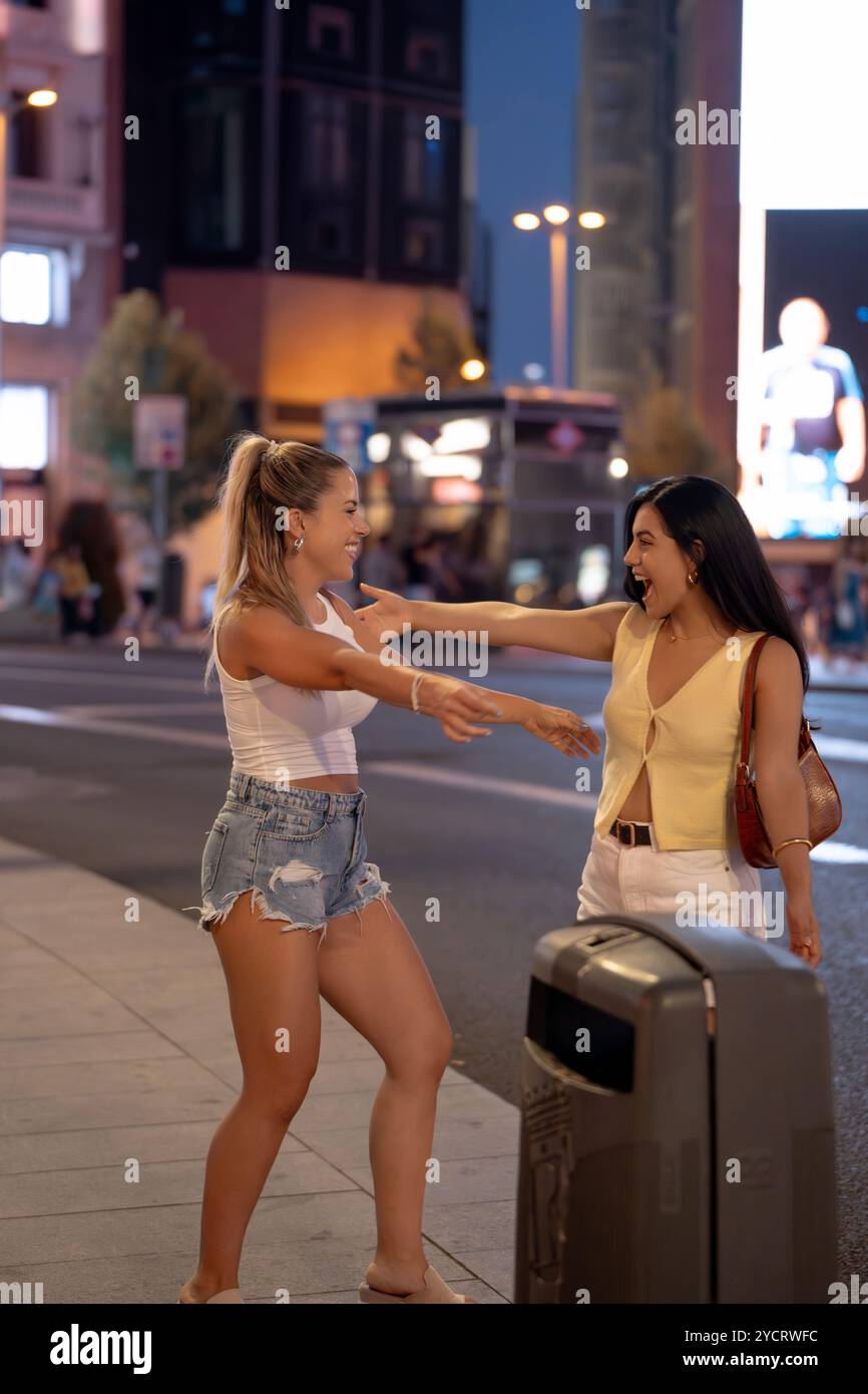 Two friends are greeting each other on a city street at night, excited ...