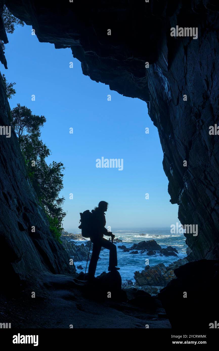 Woman hiking standing in Guano Cave and looking out to sea, Otter Trail ...