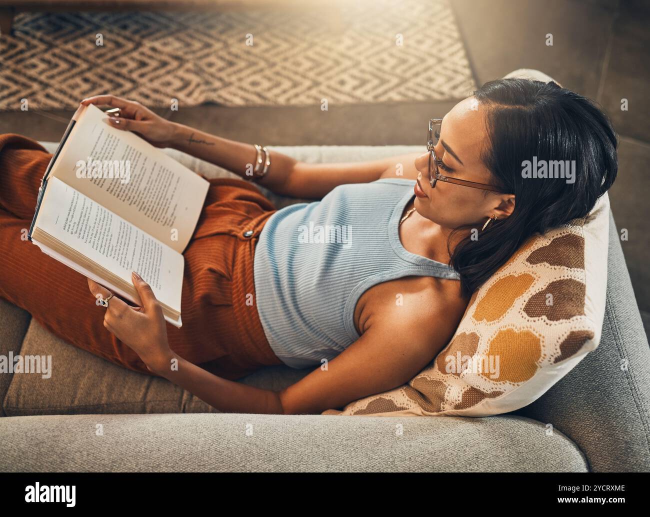 Book, reading and relax with woman on sofa in living room of home for ...