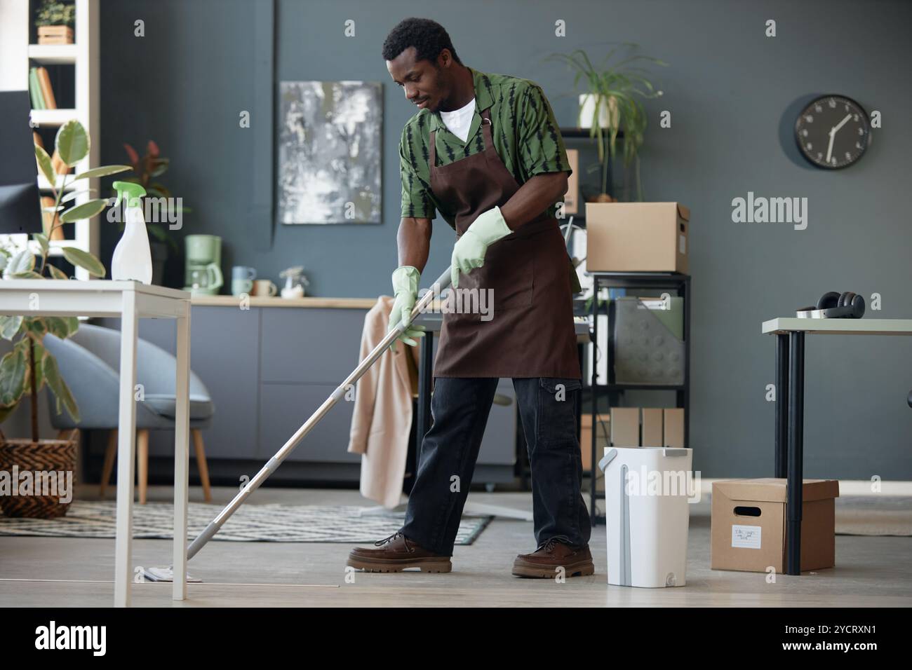 Full length side view of adult African American man mopping floors in ...