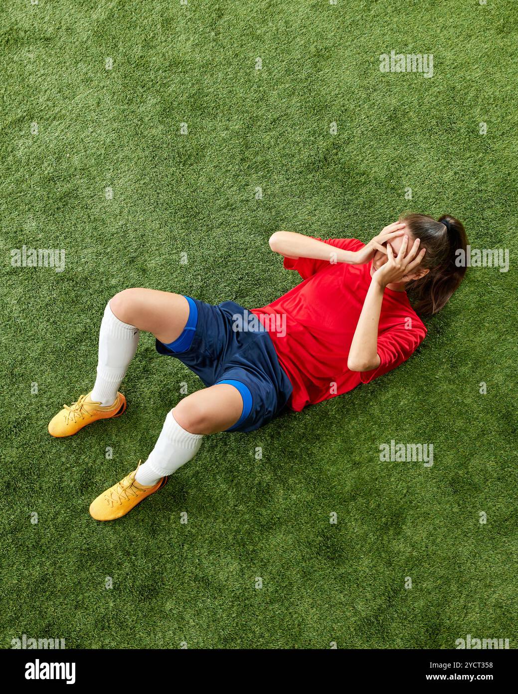Girl, soccer player lies on football field, twisted in pain. Player ...