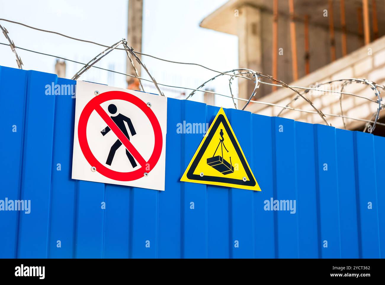 Warning signs and barbed wire on the fence at the construction site ...