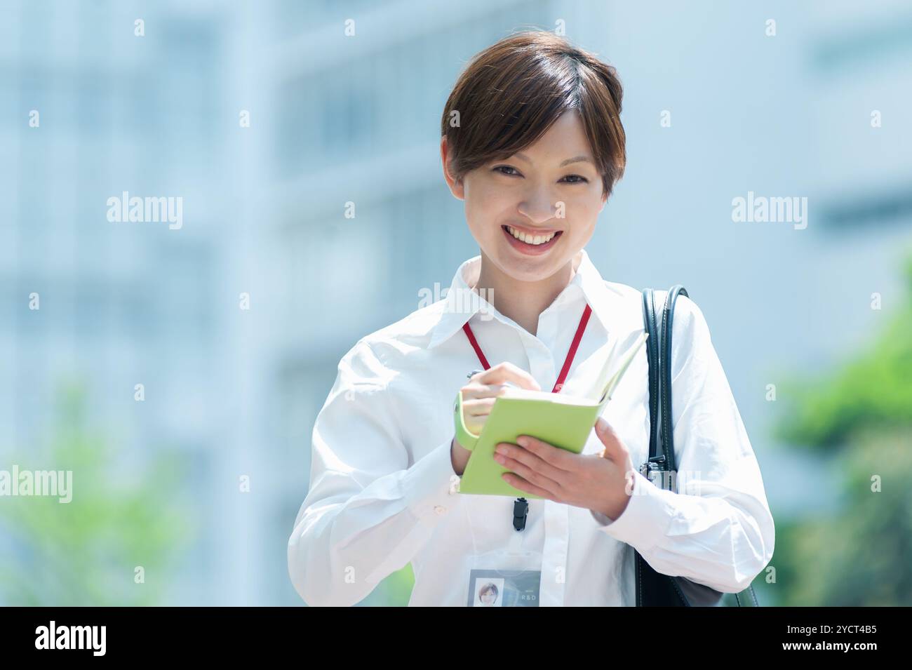 Office worker laughing while taking notes in notebook Stock Photo - Alamy