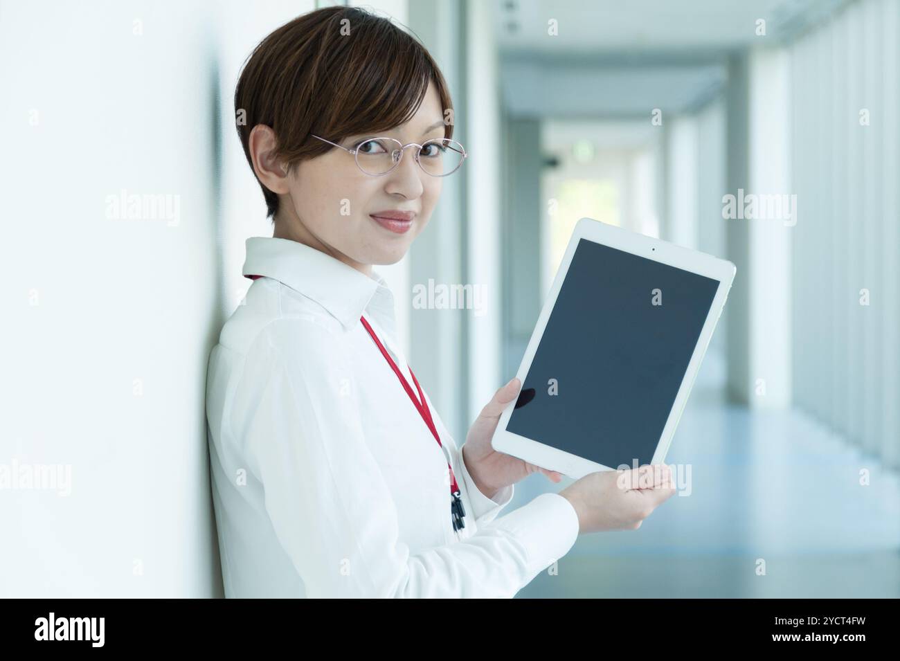 Office worker showing tablet screen in corridor Stock Photo - Alamy
