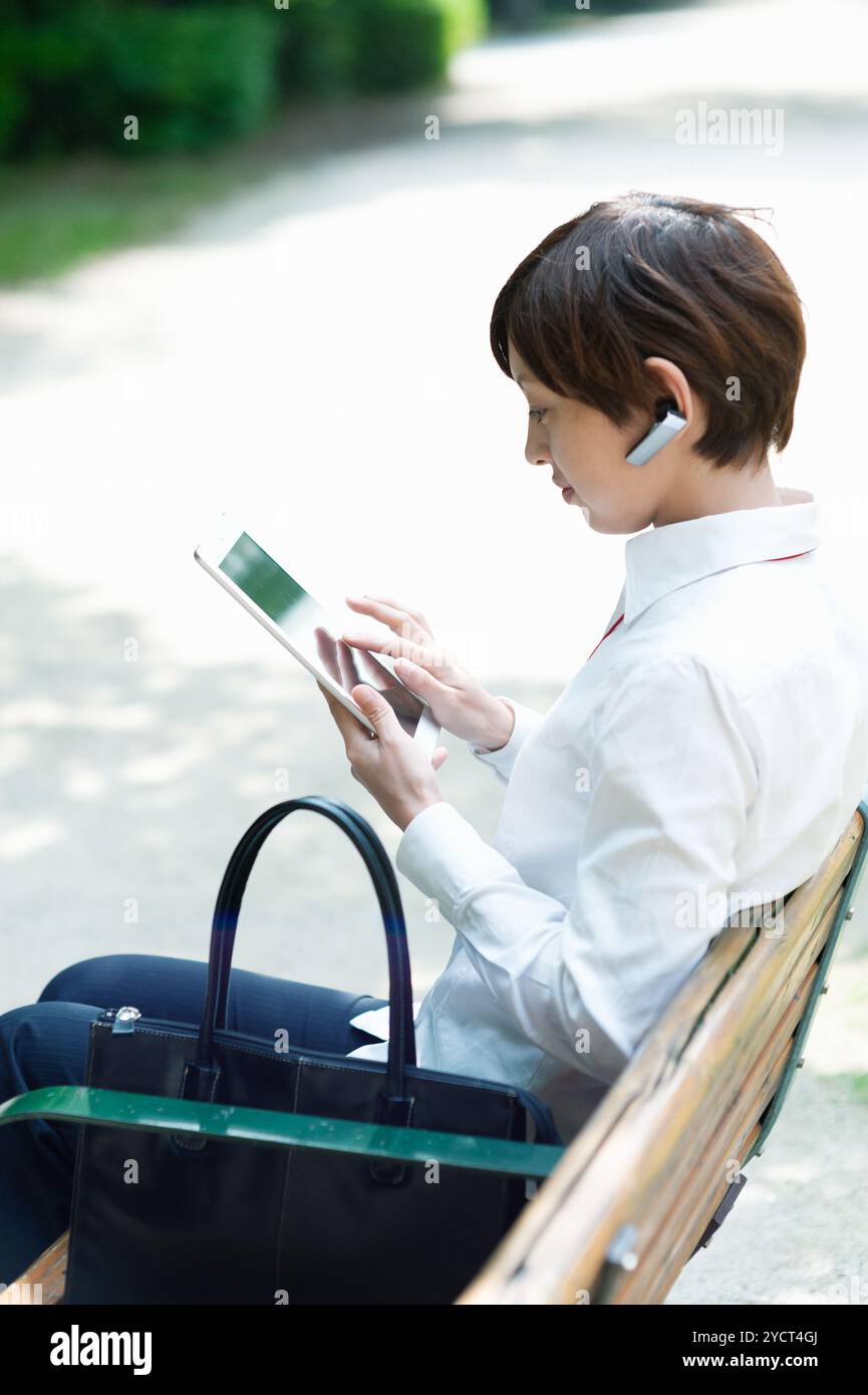 Office worker sitting on bench operating tablet Stock Photo - Alamy