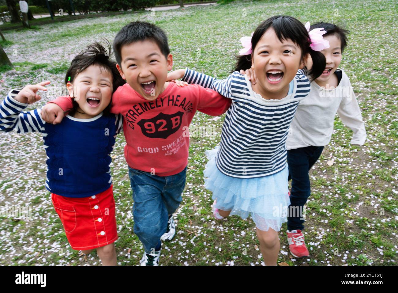 Four children running shoulder to shoulder Stock Photo - Alamy