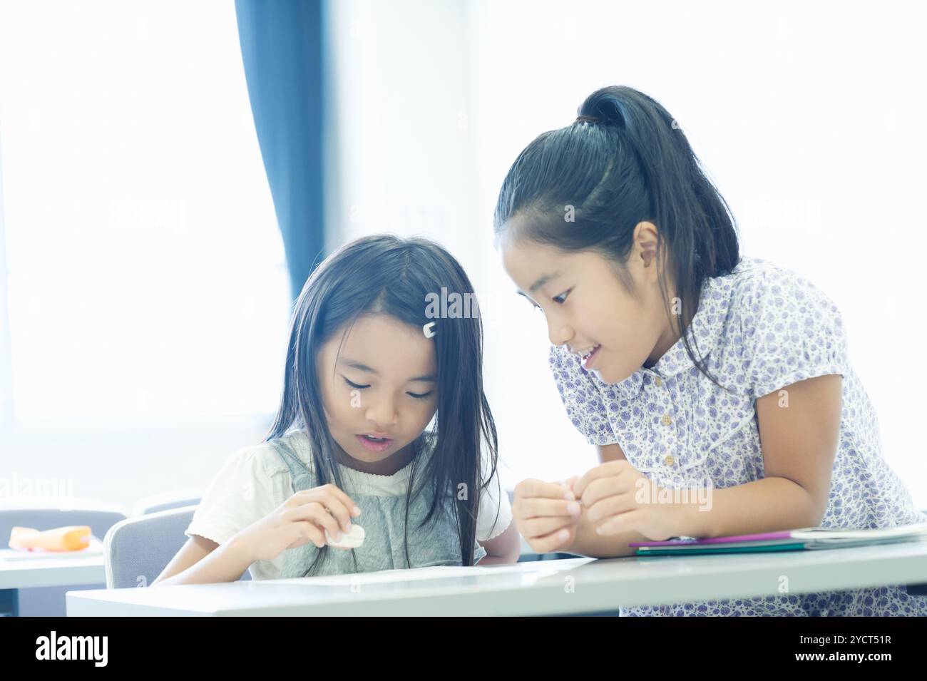 Primary schools student being taught by a friend Stock Photo - Alamy