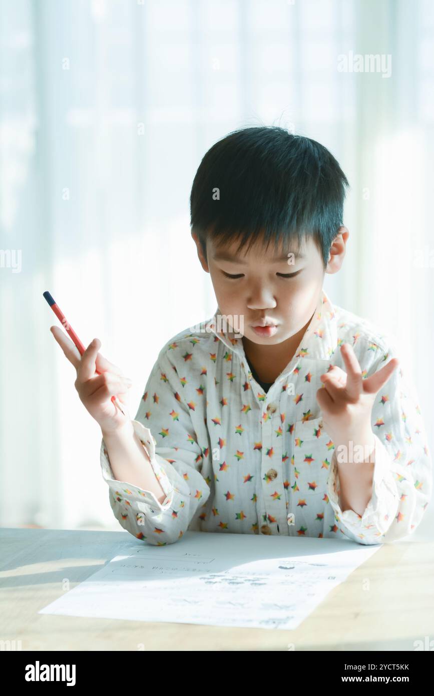 Primary school boy doing maths with his finger Stock Photo - Alamy