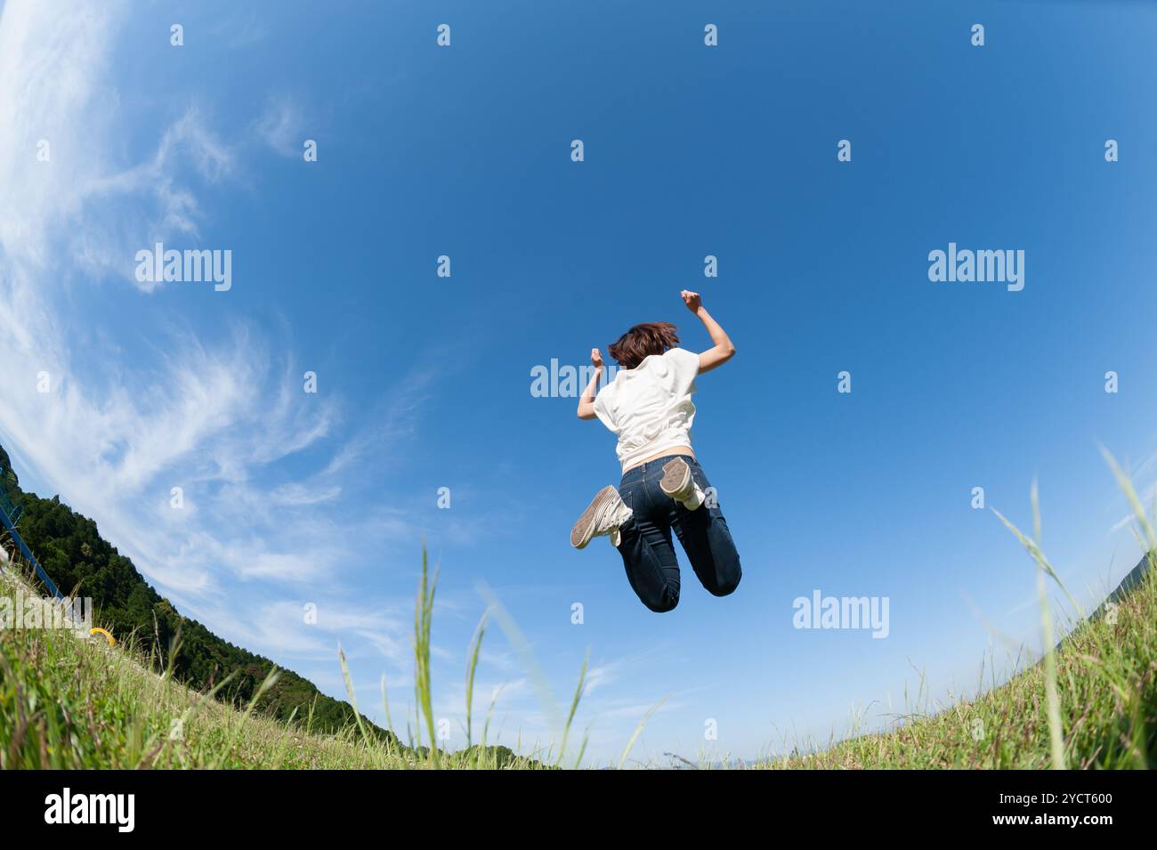 Back view of woman jumping in grassland Stock Photo - Alamy