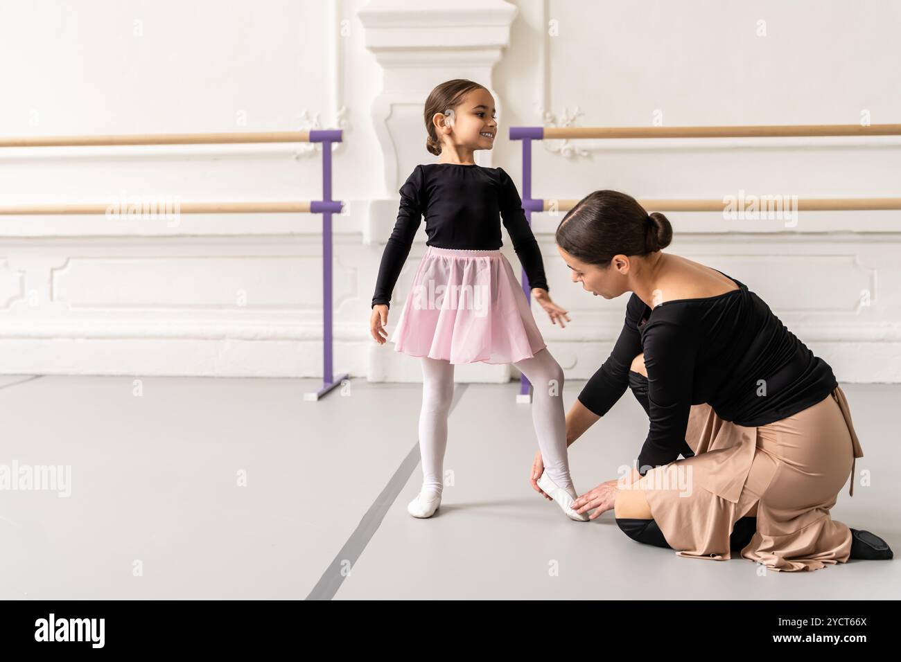 Elegant female trainer coaching young girl in classic ballet lesson ...