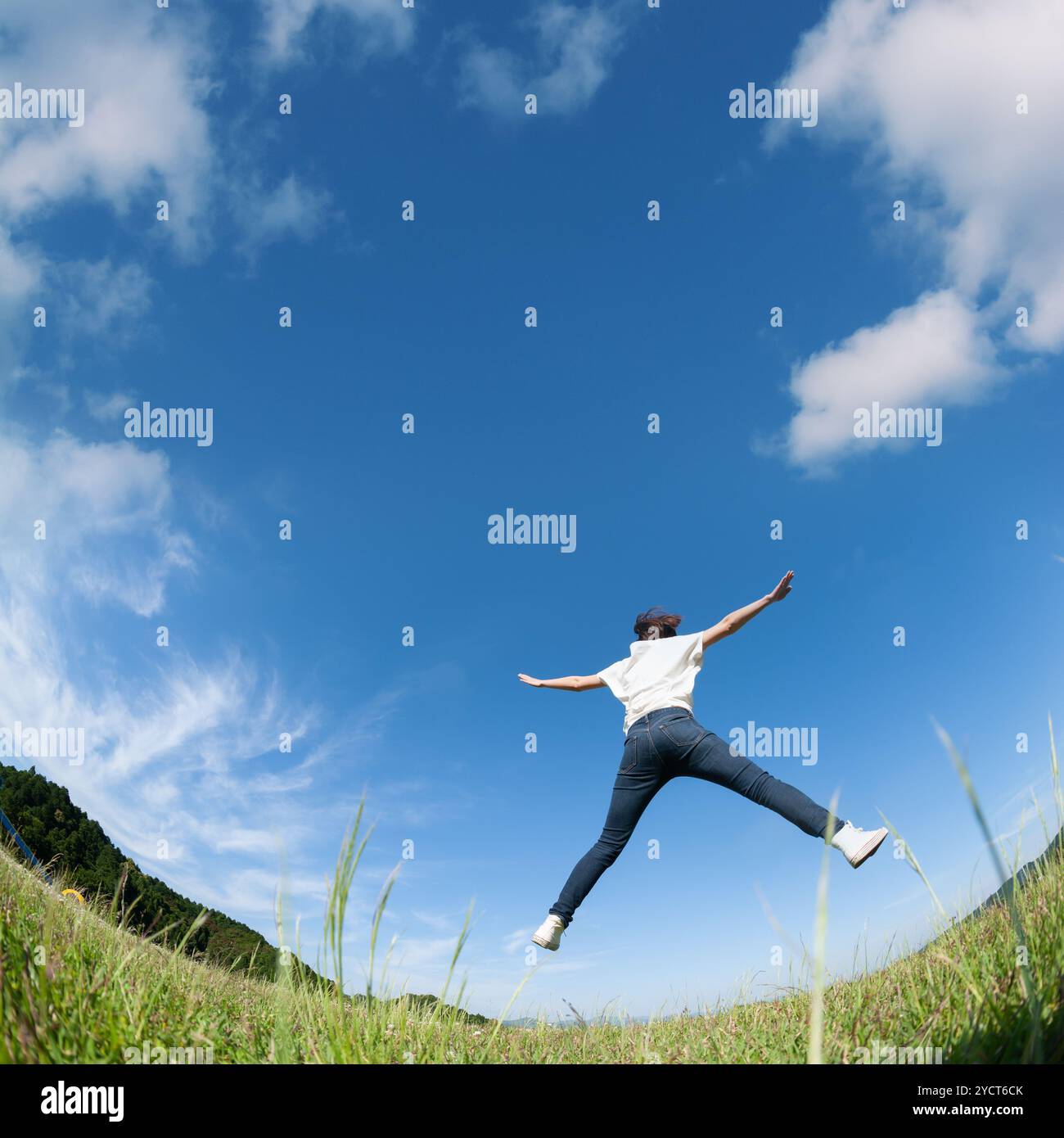 Back view of woman jumping in grassland Stock Photo - Alamy
