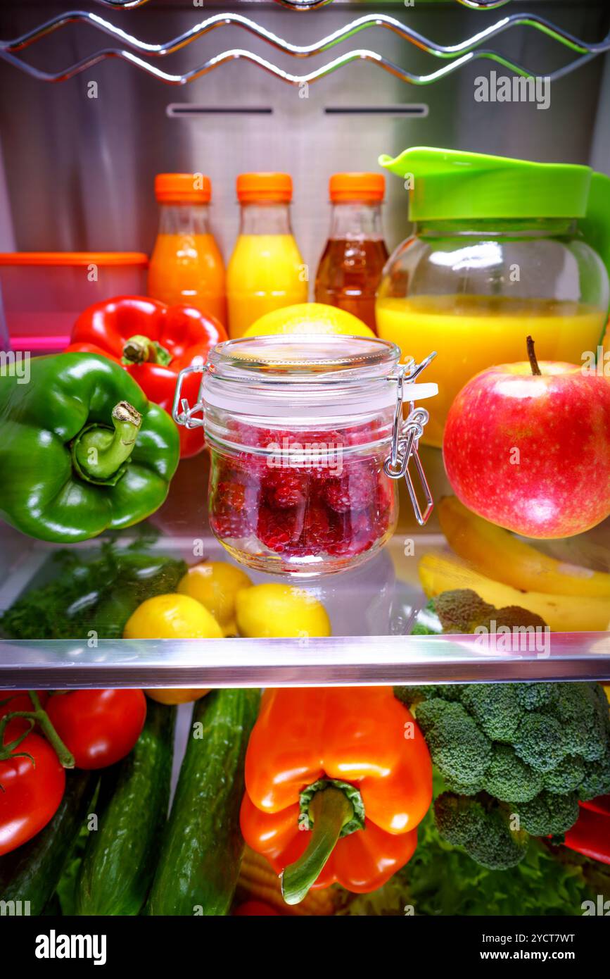 Fresh raspberries in a glass jar on a shelf open refrigerator Stock ...