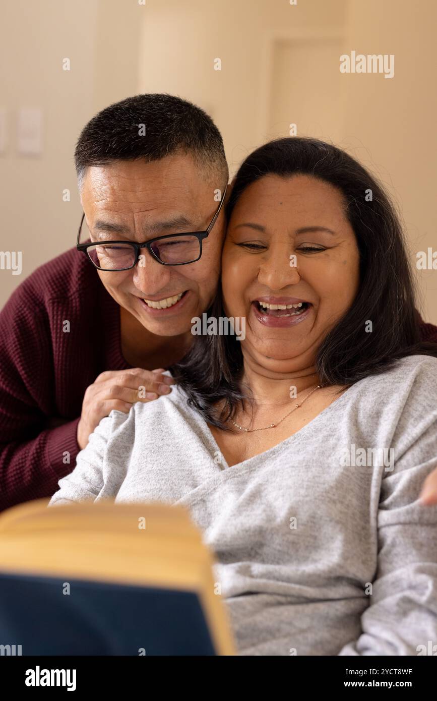 Happy Multiracial senior couple reading book together, sharing joyful ...