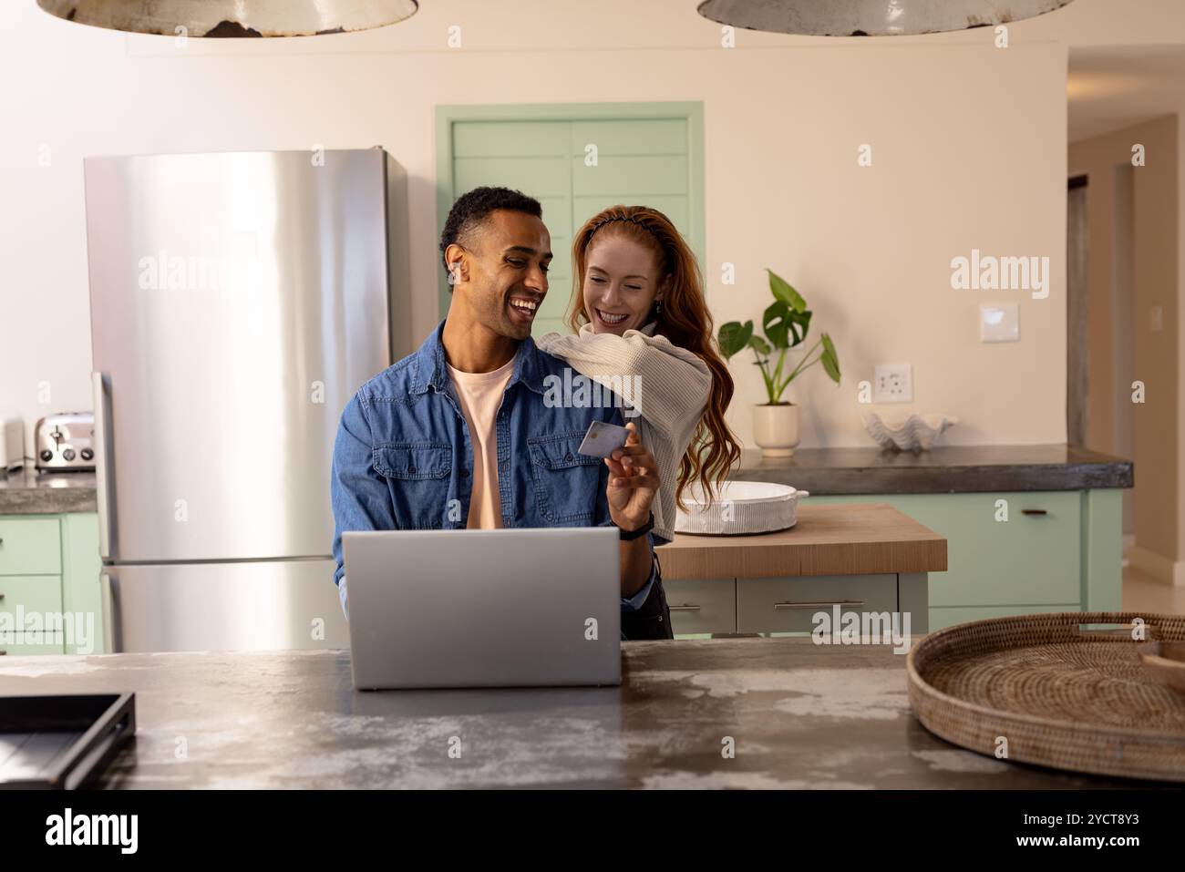 multiracial couple shopping online for Christmas gifts in cozy kitchen ...
