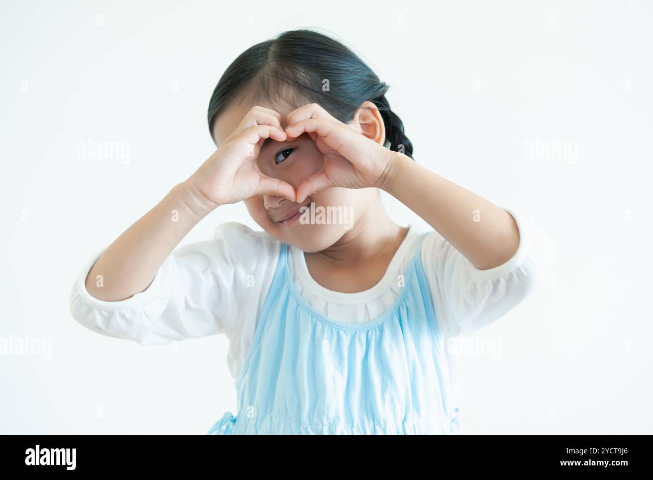 Girls making hearts with their hands and peeking in Stock Photo - Alamy