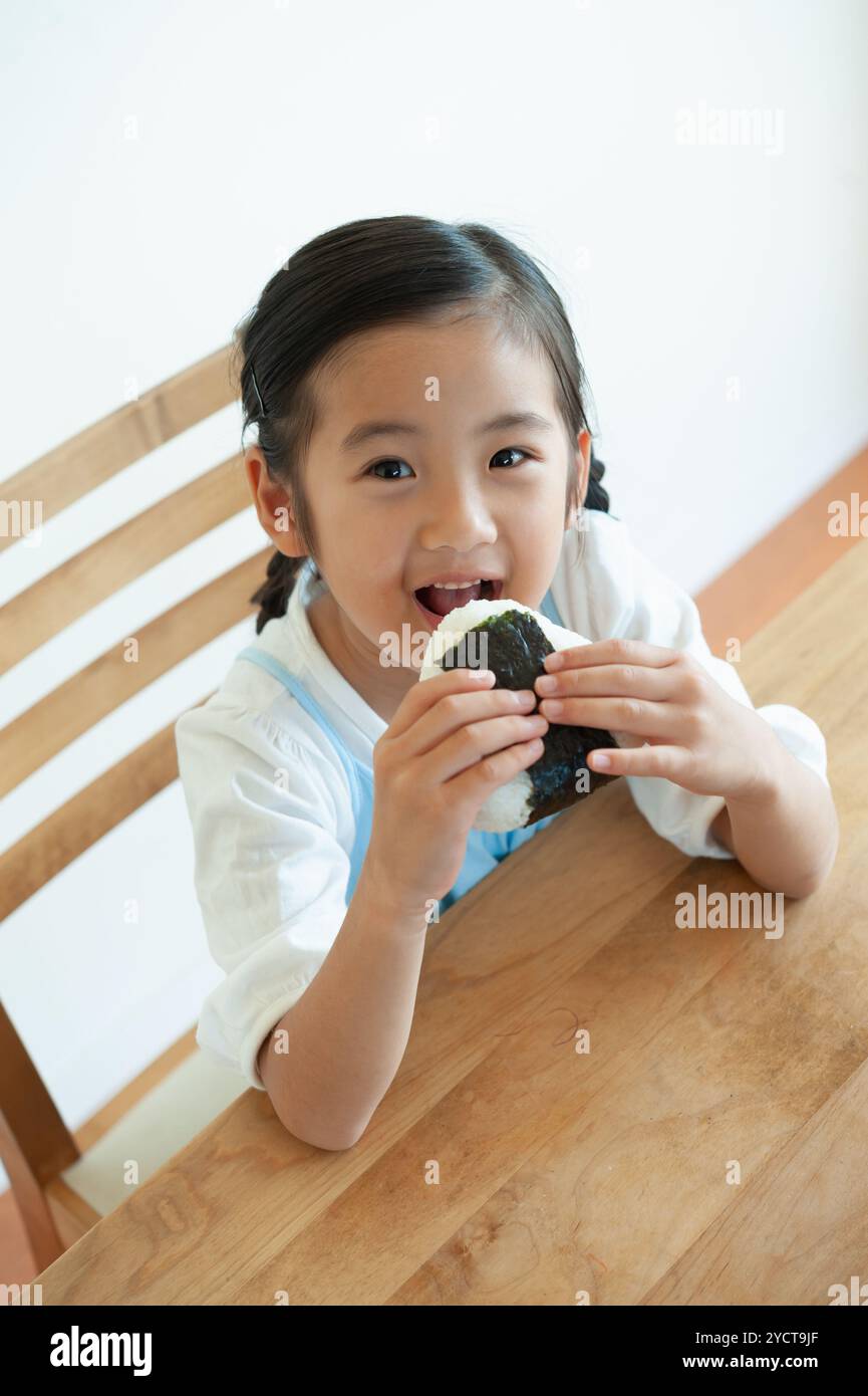 Girl eating an onigiri Stock Photo - Alamy