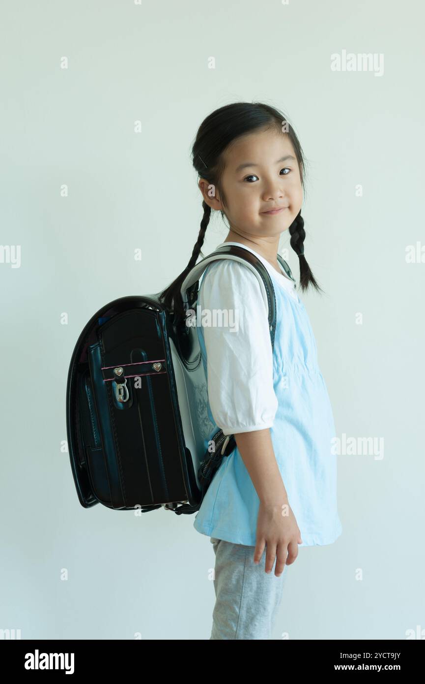 Girl carrying school backpack facing sideways Stock Photo - Alamy