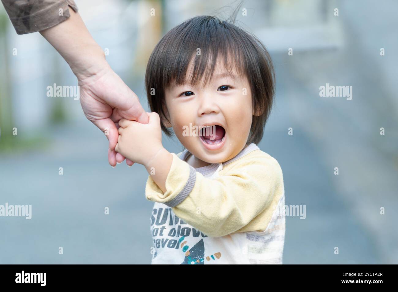 Boy looking back while holding hands with his mother Stock Photo - Alamy