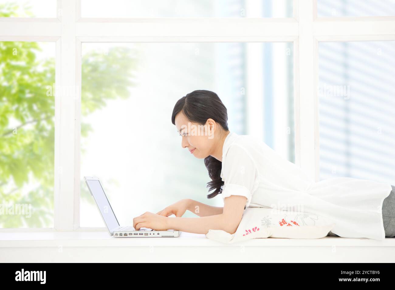 Woman lying down and opening computer Stock Photo - Alamy