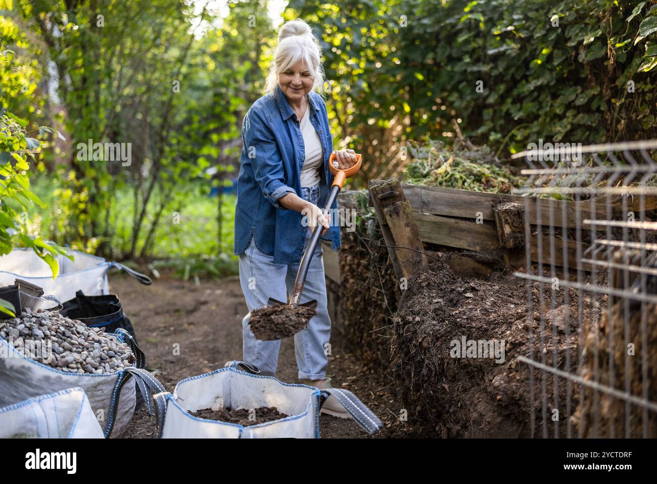 Senior woman shoveling compost heap in her garden Stock Photo - Alamy