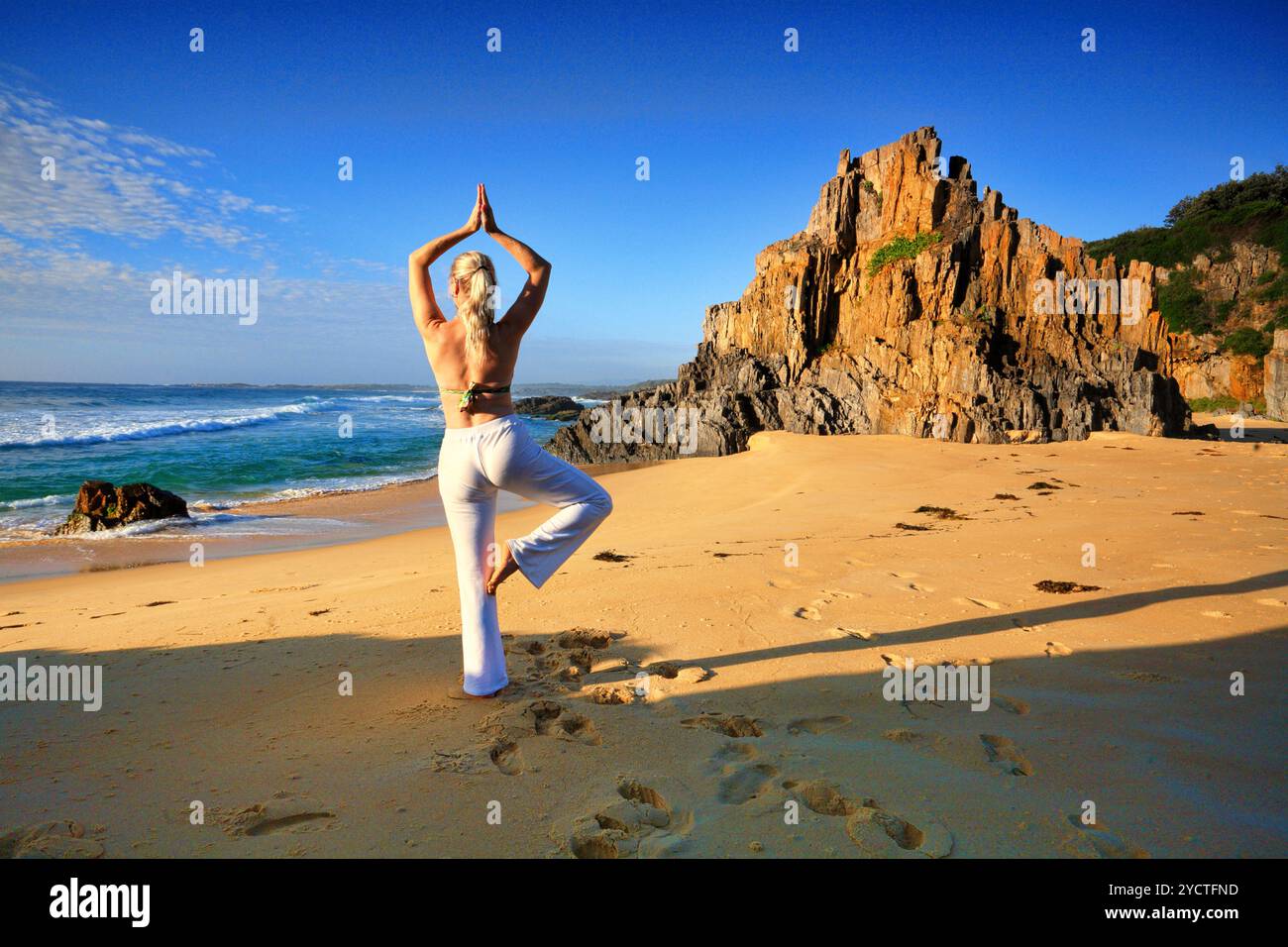 Female stretching on one leg yoga tree pose vrksasana by the beach ...