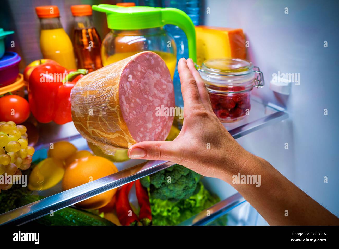 Human hands reaching for food at night in the open refrigerator Stock ...