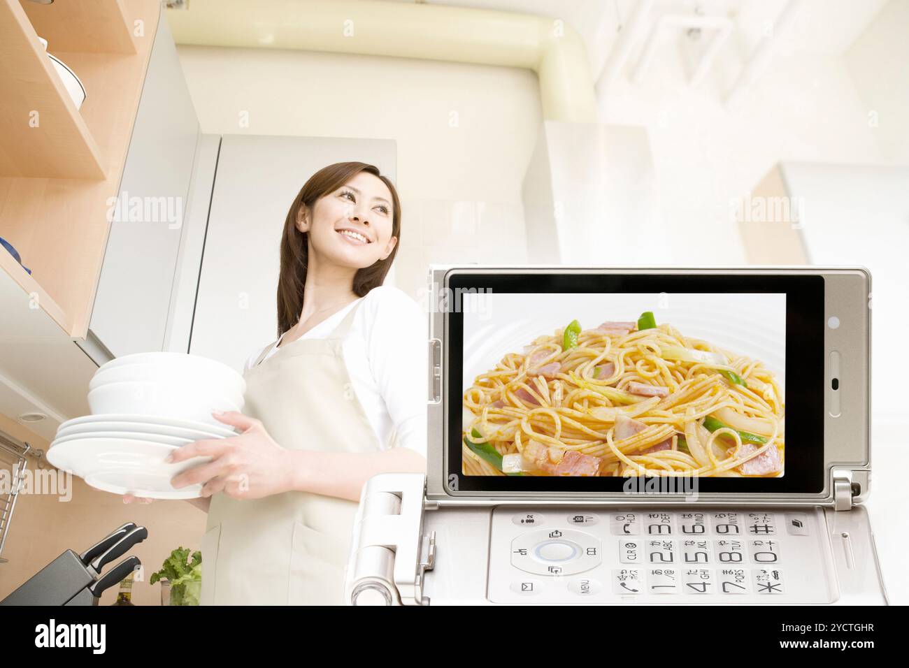 Woman putting away dishes and food on mobile phone screen Stock Photo ...