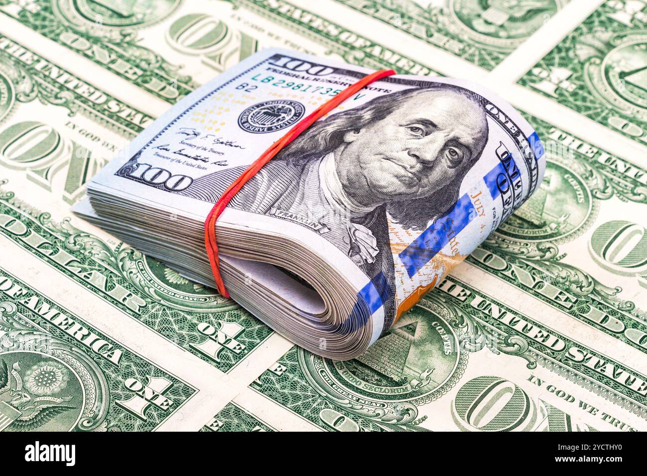 Folded dollar bills wrapped by rubber band over dollars banknotes Stock ...