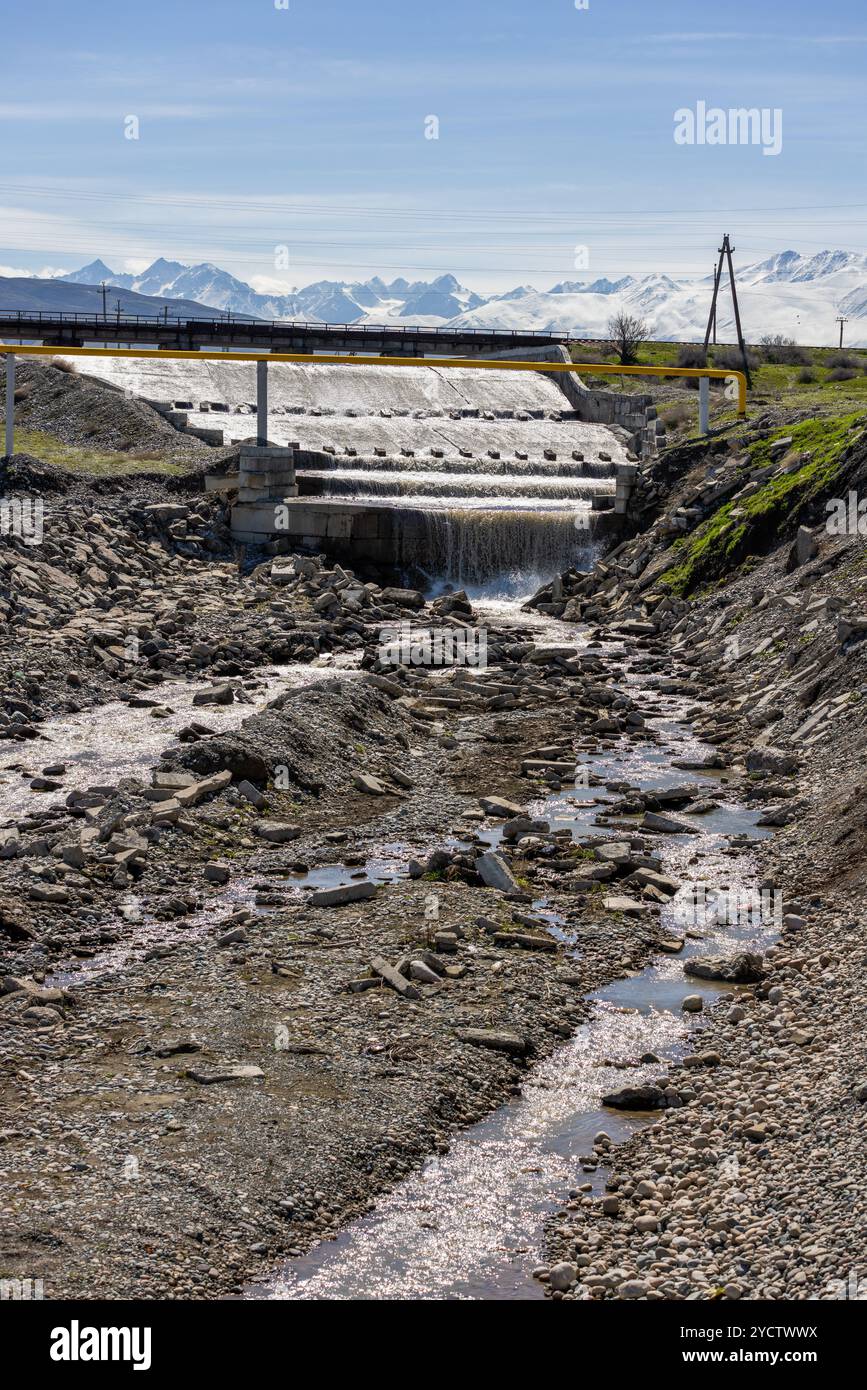 cascade concrete water spillway channel on mountain river with mountain ...