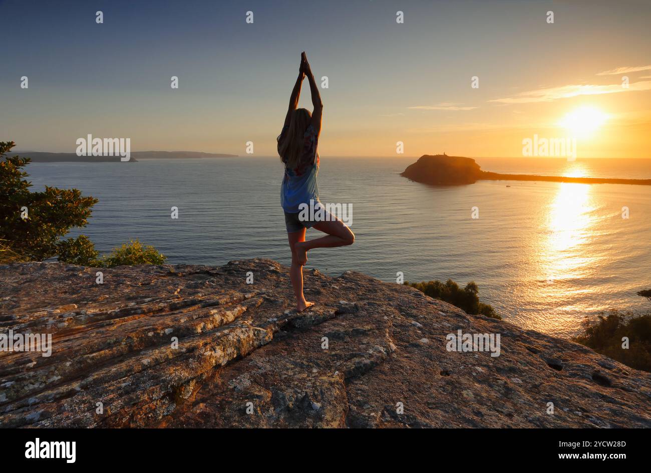 Yoga by the Sea at sunrise - Tree Pose Vrksasana Stock Photo - Alamy
