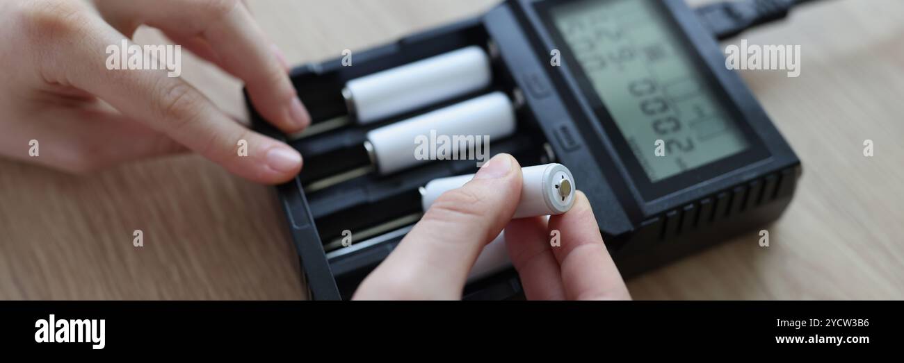 Female hands insert cells for battery into charger. Device for ...