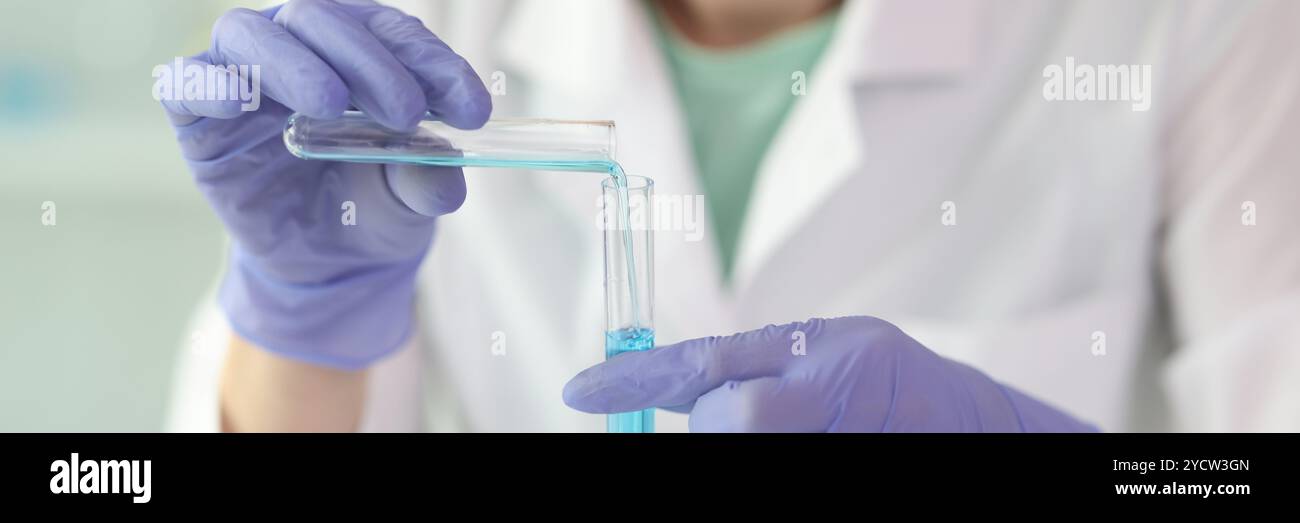 Female laboratory assistant pours blue liquid from test tube Stock ...