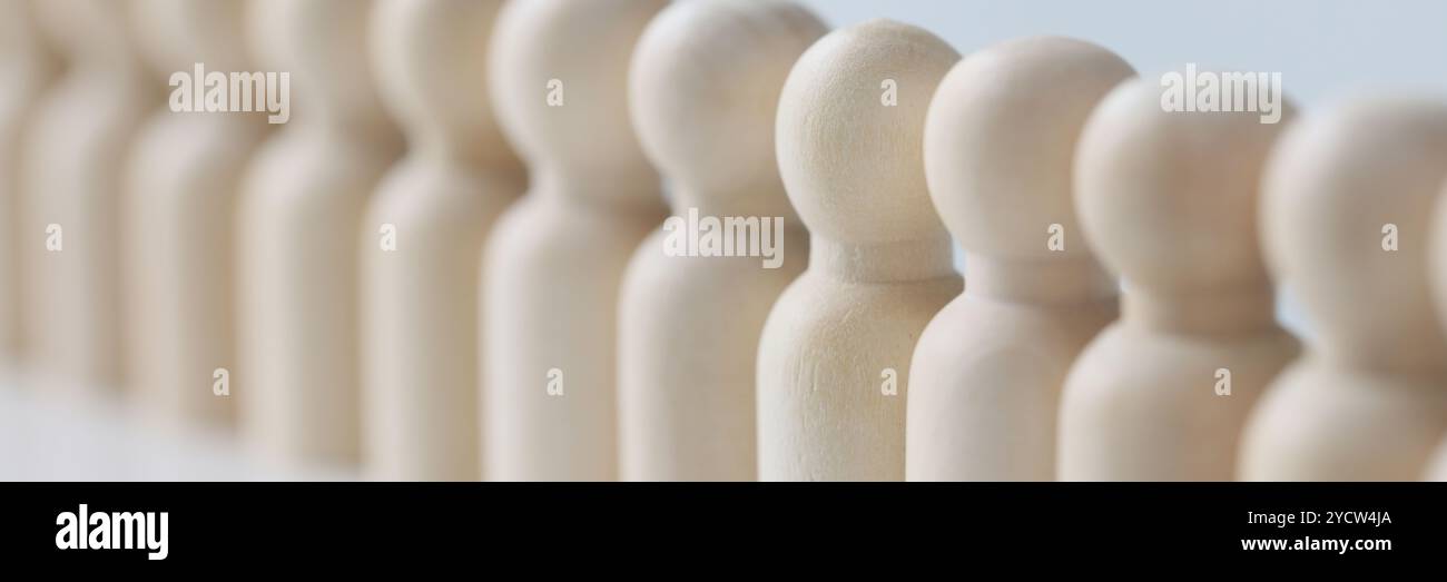 Small wooden figures lined up in long row on white table Stock Photo ...