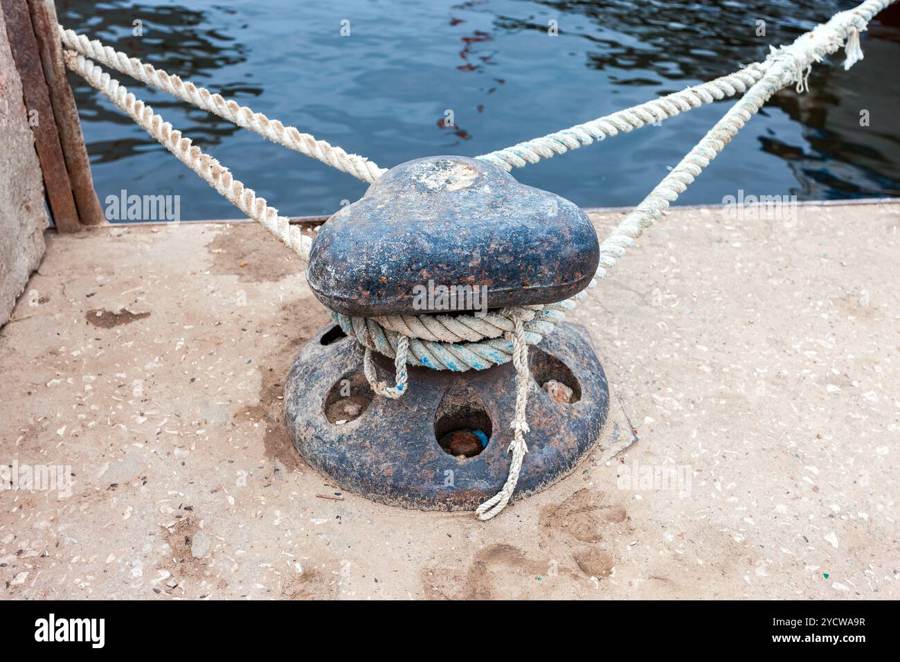 Old mooring metal bollard with a fixed rope at the pier Stock Photo - Alamy