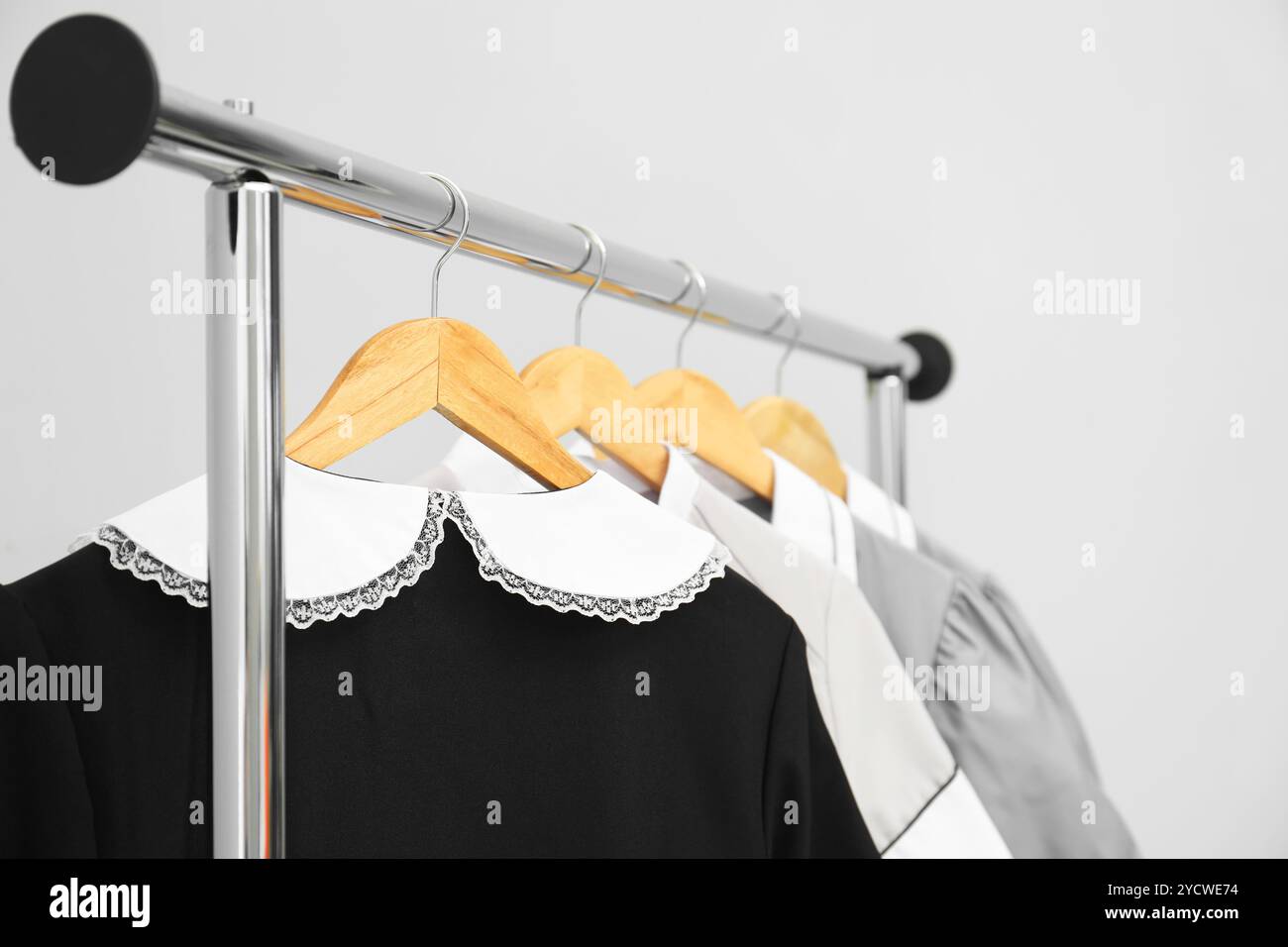 Maids' uniforms on clothing rack against grey background, closeup Stock ...