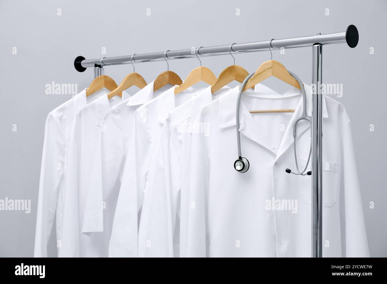 Different medical workers' uniforms and stethoscope on clothing rack ...