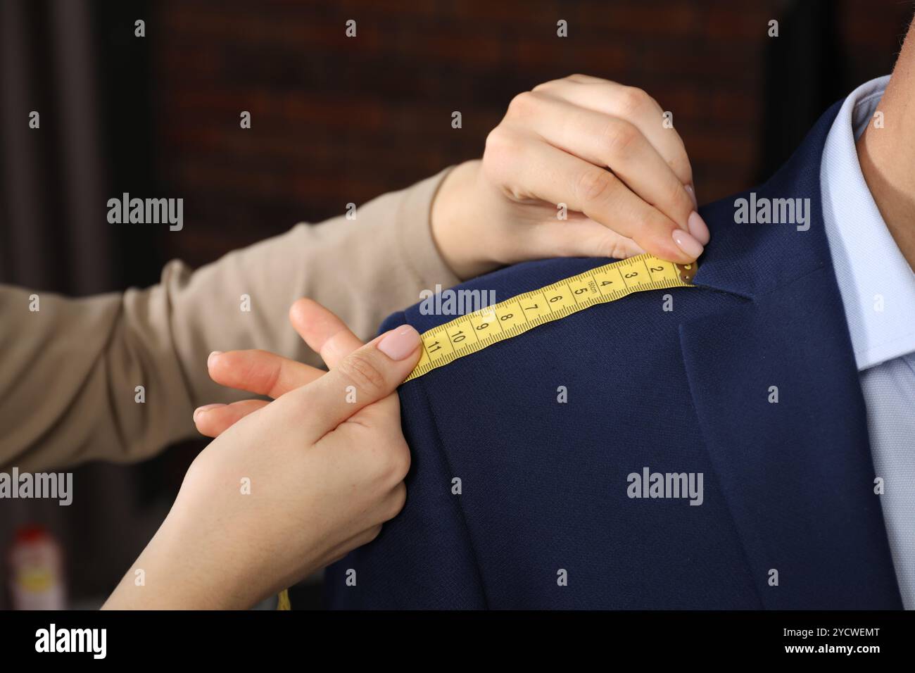 Professional tailor measuring shoulder seam length on client's jacket ...