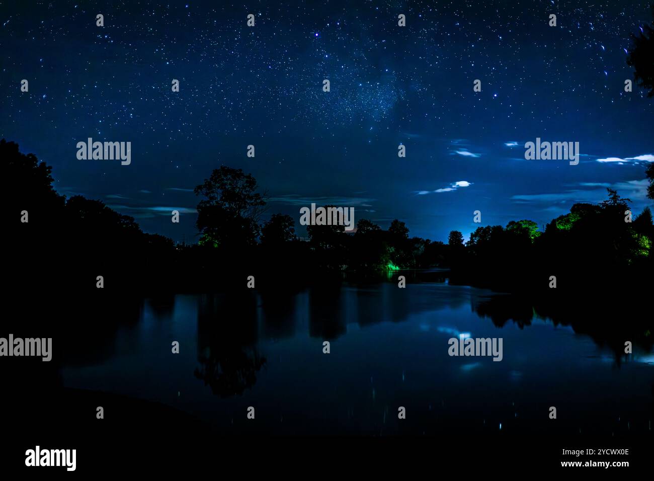 Starry night sky over the river and its reflection in the still water ...