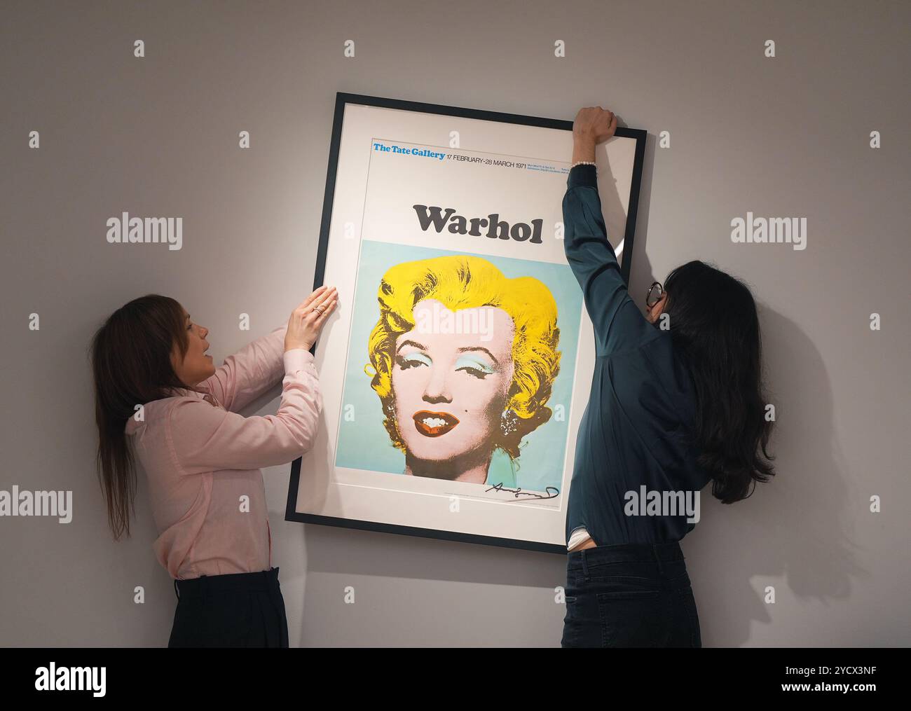 Members of gallery staff position a signed Tate Gallery poster by Andy ...
