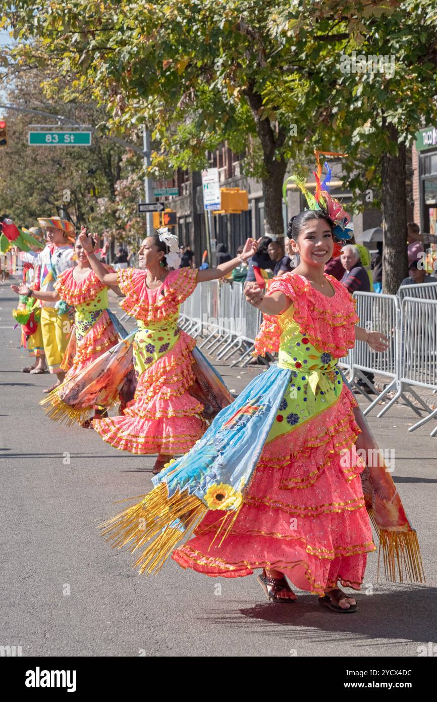 A line of dancers in orange dresses at the 2024 Bolivian Day Parade in ...