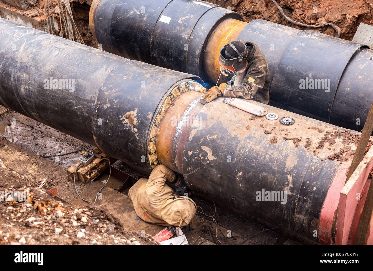 The workers, welders made by electric welding on large iron pipes at a ...