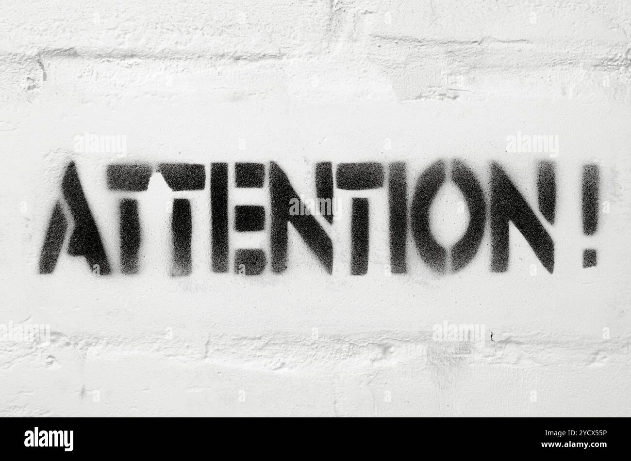 attention word textured stencil print on the white brick wall Stock ...