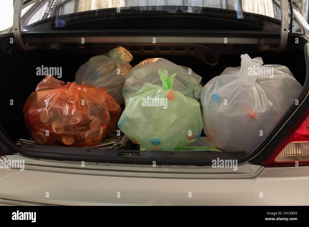 A car trunk filled with color-coded plastic bags containing recyclable ...