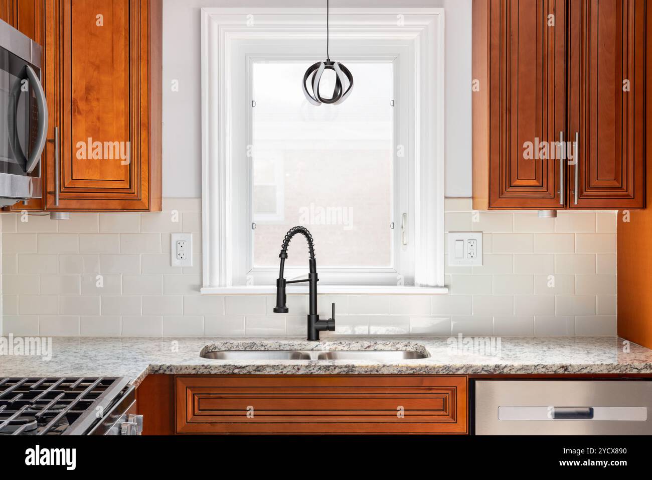 A kitchen sink detail in front of a window with a marble countertop ...