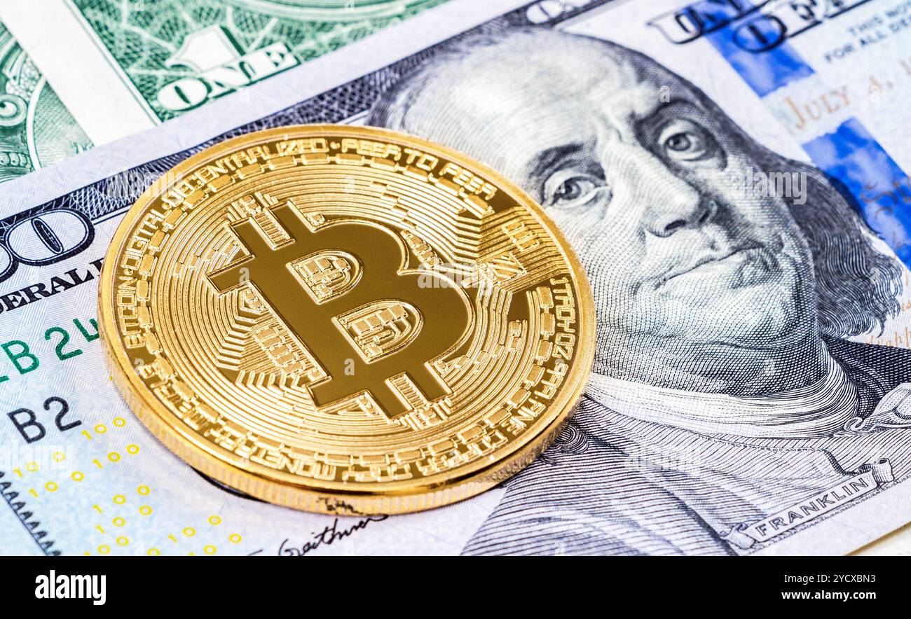 Golden bitcoin lying over one hundred american dollar bill close up ...