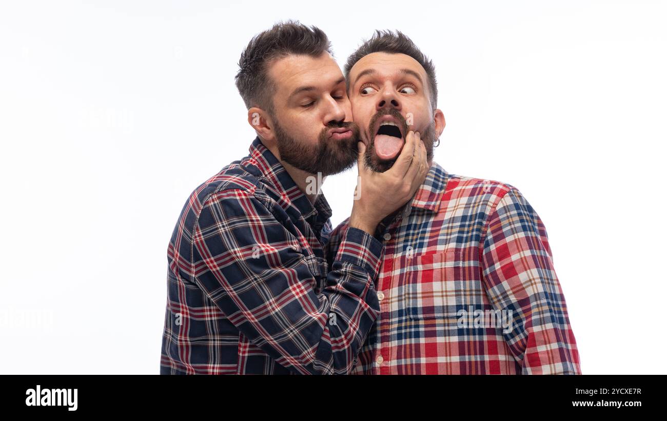 Two men, twins in plaid shirts, one playfully grabbing other's face ...